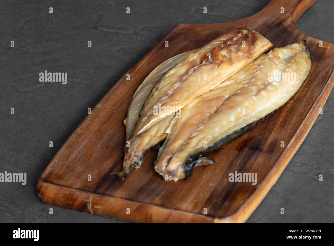 Raw smoked mackerel fillets on a rustic wooden chopping board. With a ...
