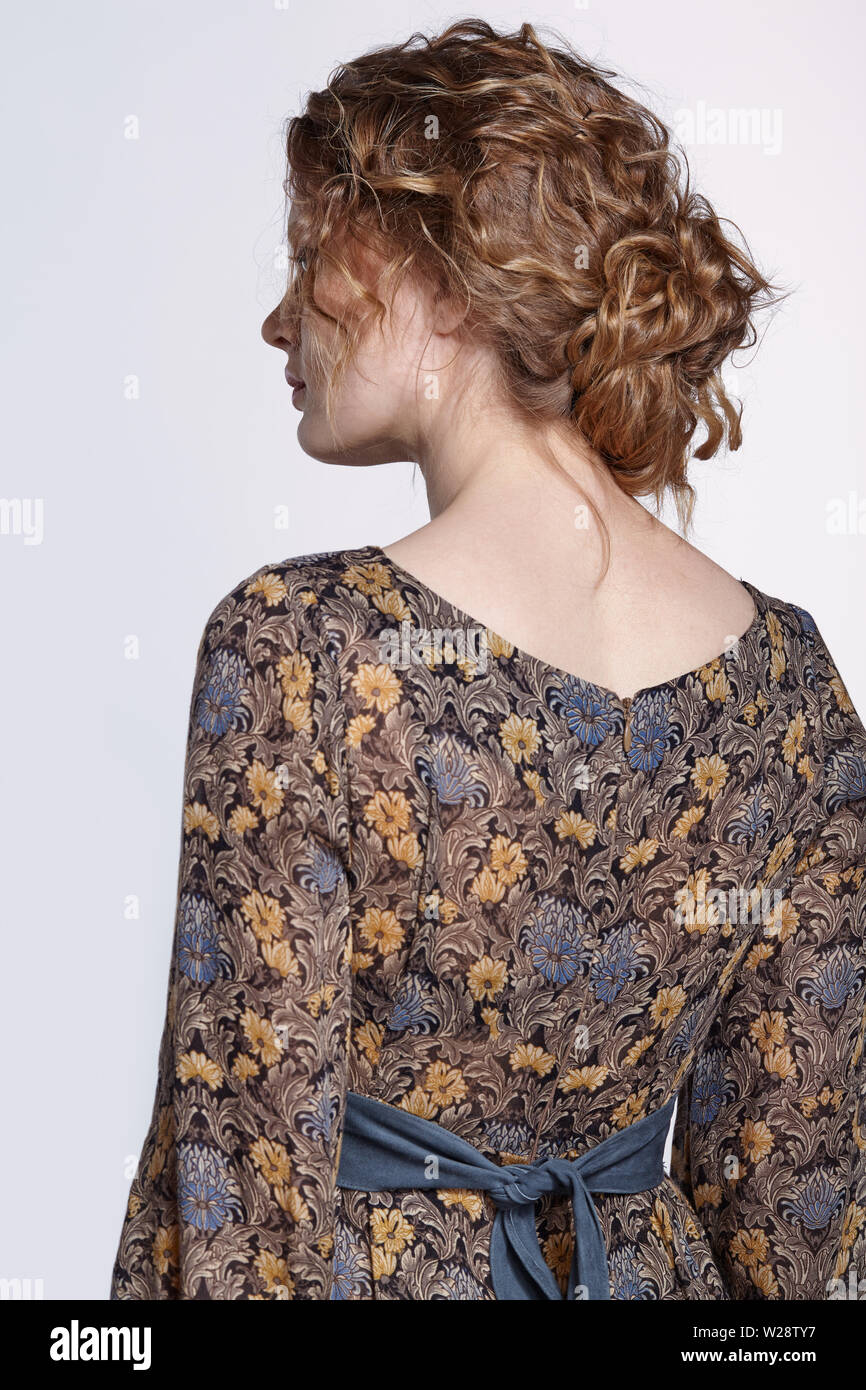 Portrait of a young caucasian woman in vintage retro dress from back ...