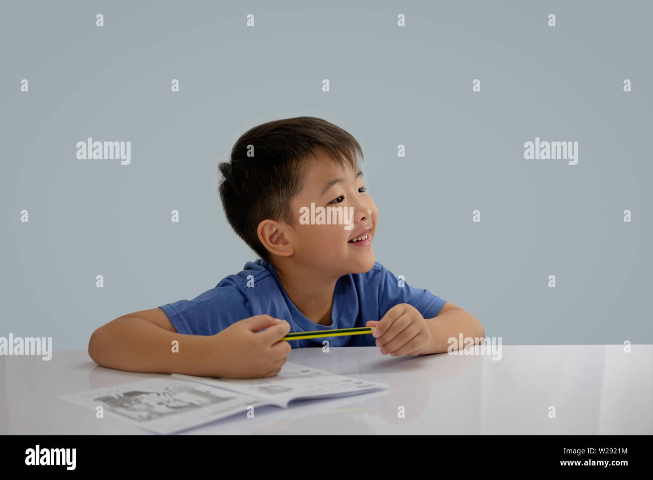 Asian boys are doing some writing on the book isolated on blue ...