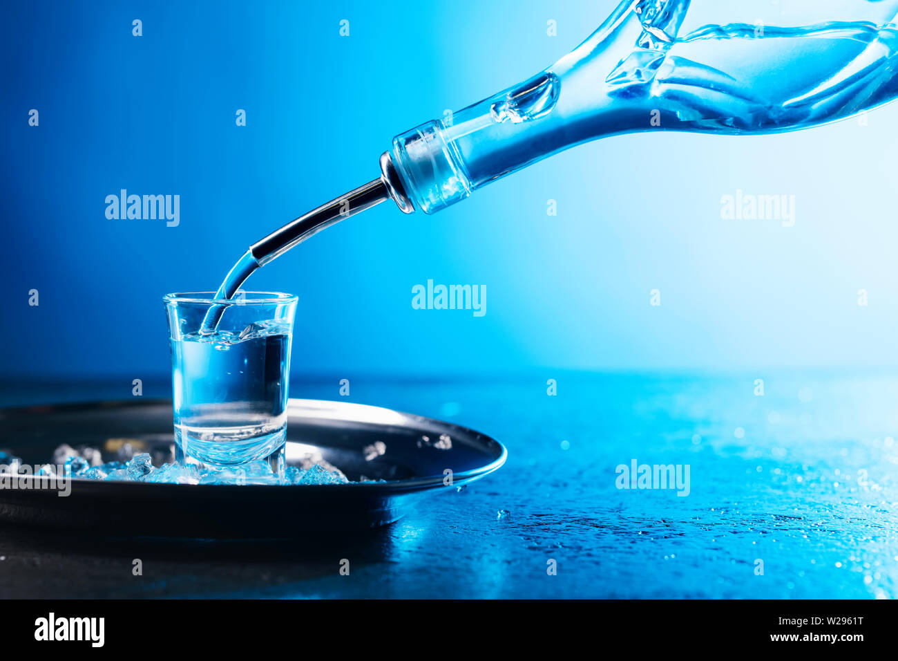 Vodka poured into a glass lit with blue backlight. Copy space.Chilled ...
