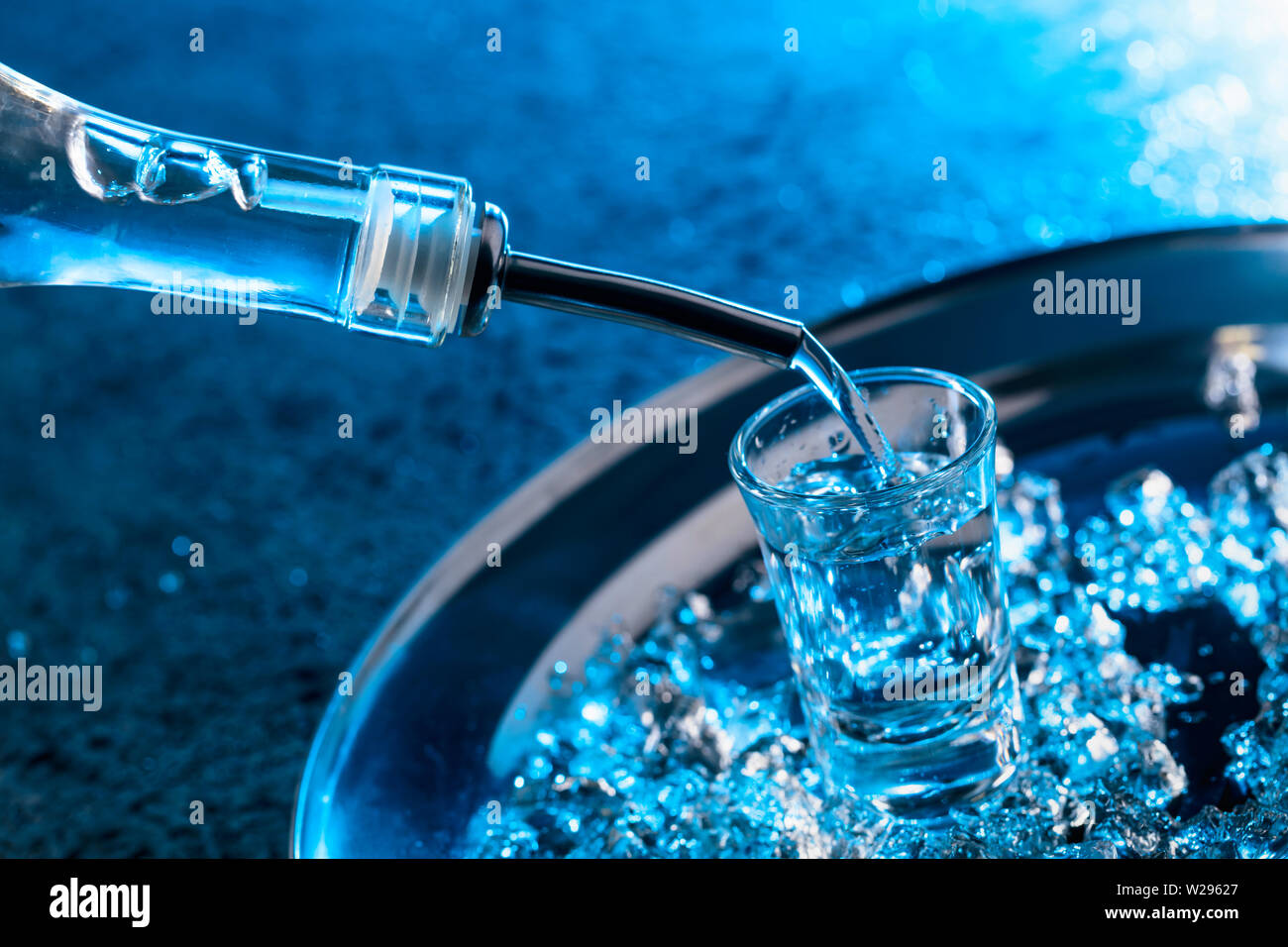 Vodka poured into a glass lit with blue backlight.Chilled vodka with ...
