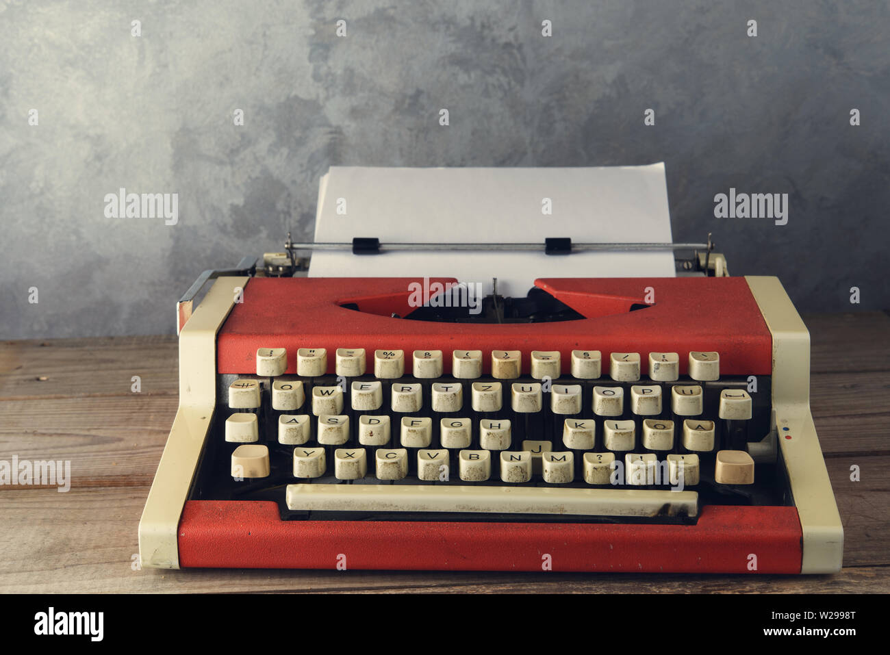 Old red typewriter on the table near the wall Stock Photo - Alamy