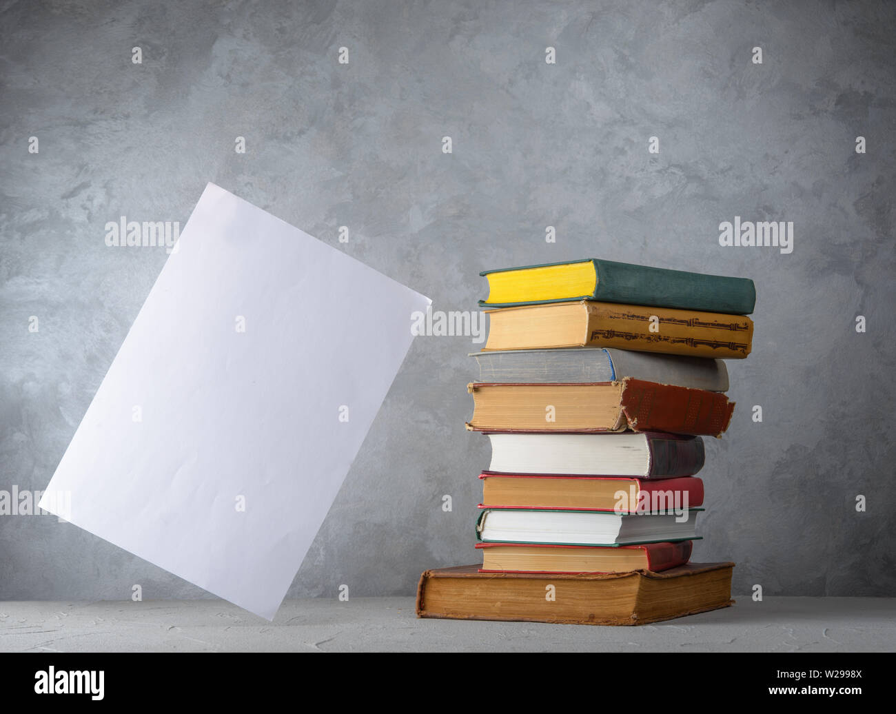 Stack of books on the table and white paper sheet Stock Photo - Alamy