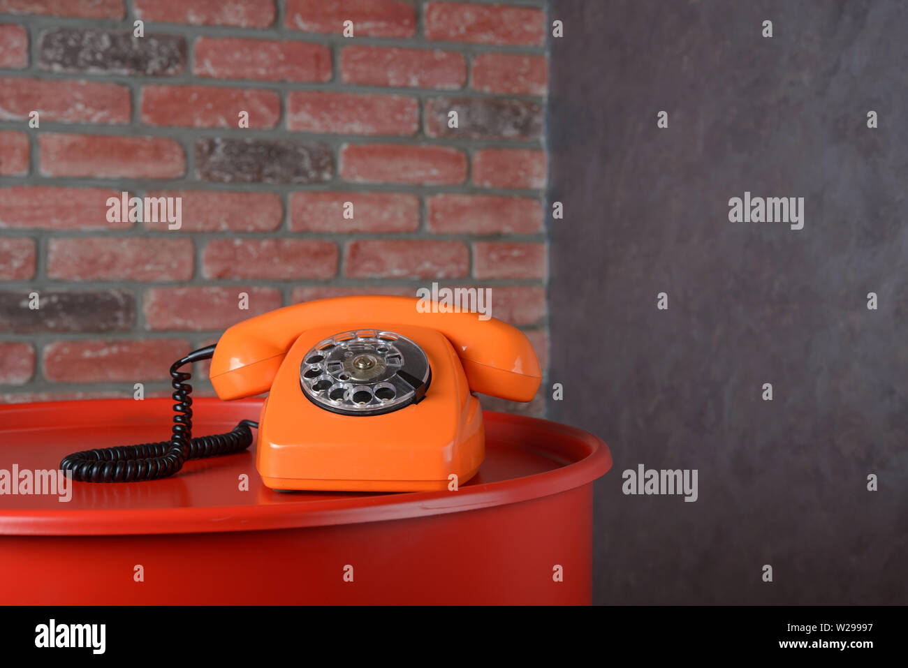 Vintage orange telephone on brick wall background Stock Photo - Alamy