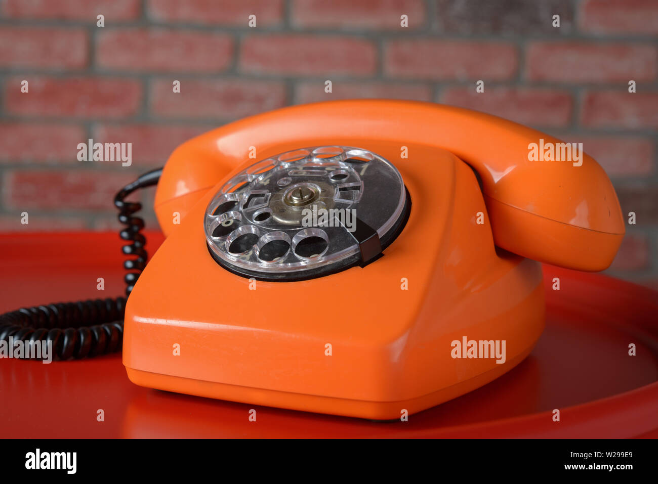 Vintage orange telephone on brick wall background Stock Photo - Alamy