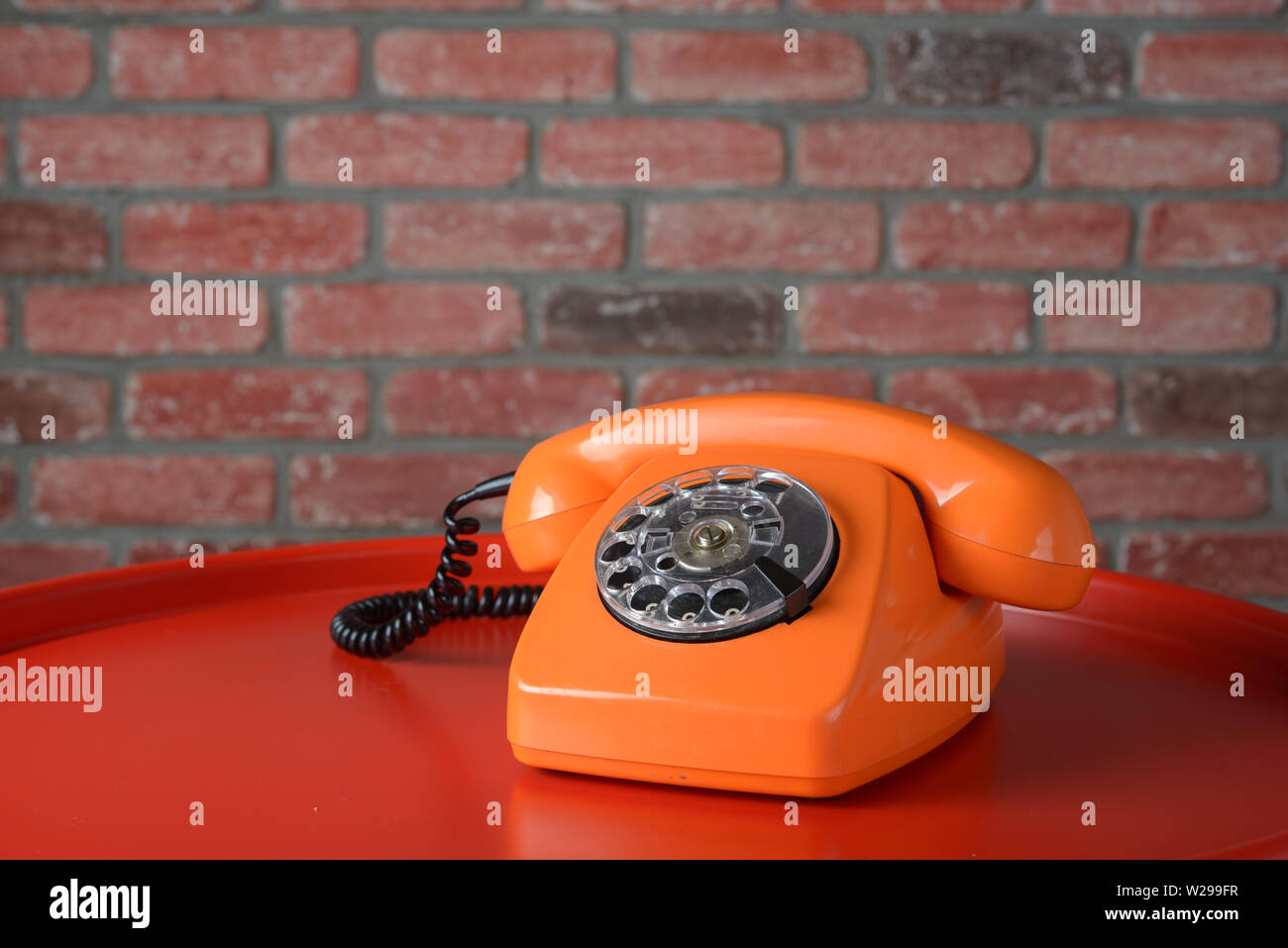 Vintage orange telephone on brick wall background Stock Photo - Alamy