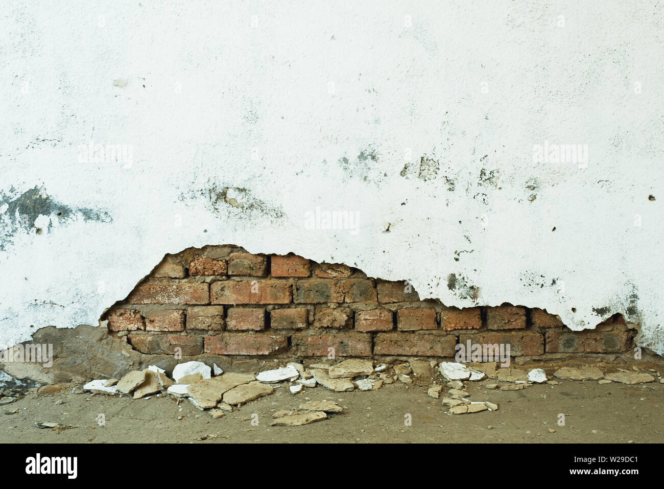 orange bricks peeking out from under a white peeling wall. destroyed ...