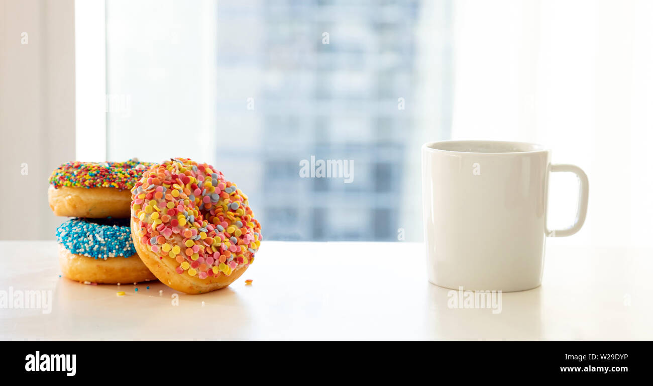 Donuts and coffee for breakfast. Colorful donuts and cup of coffee on ...