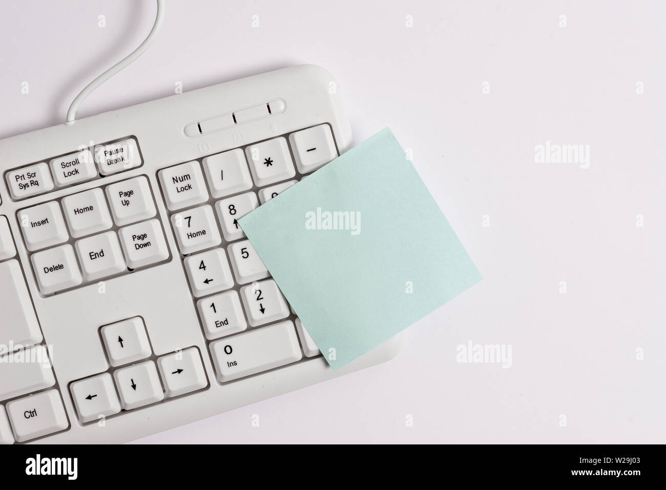 White pc keyboard with empty note paper above white background ...