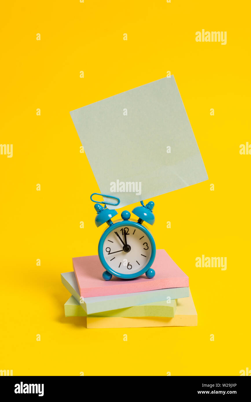 Metal alarm clock blank sticky note stacked notepads colored background ...