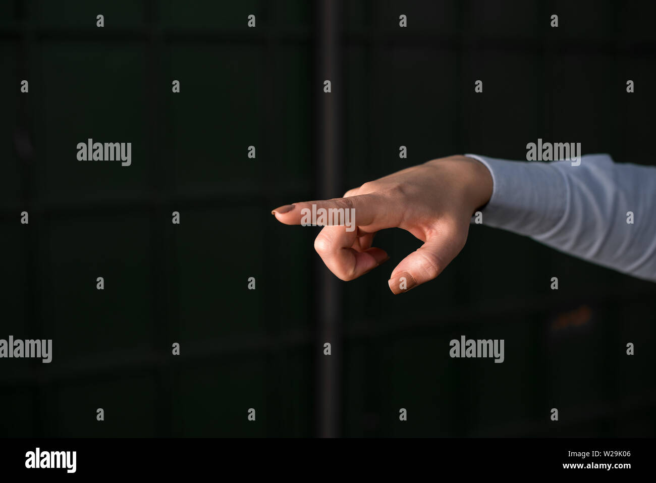 Finger pointing in the empty space. Dark background with hand pointing ...