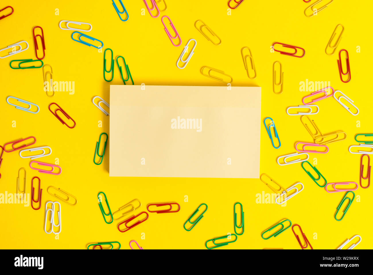 Flat lay above empty paper with copy space and colored paper clips ...