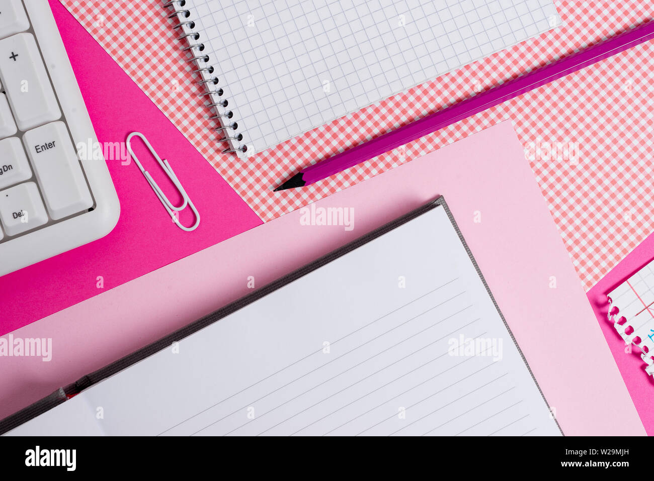 Writing equipments and computer stuffs placed above colored plain table ...