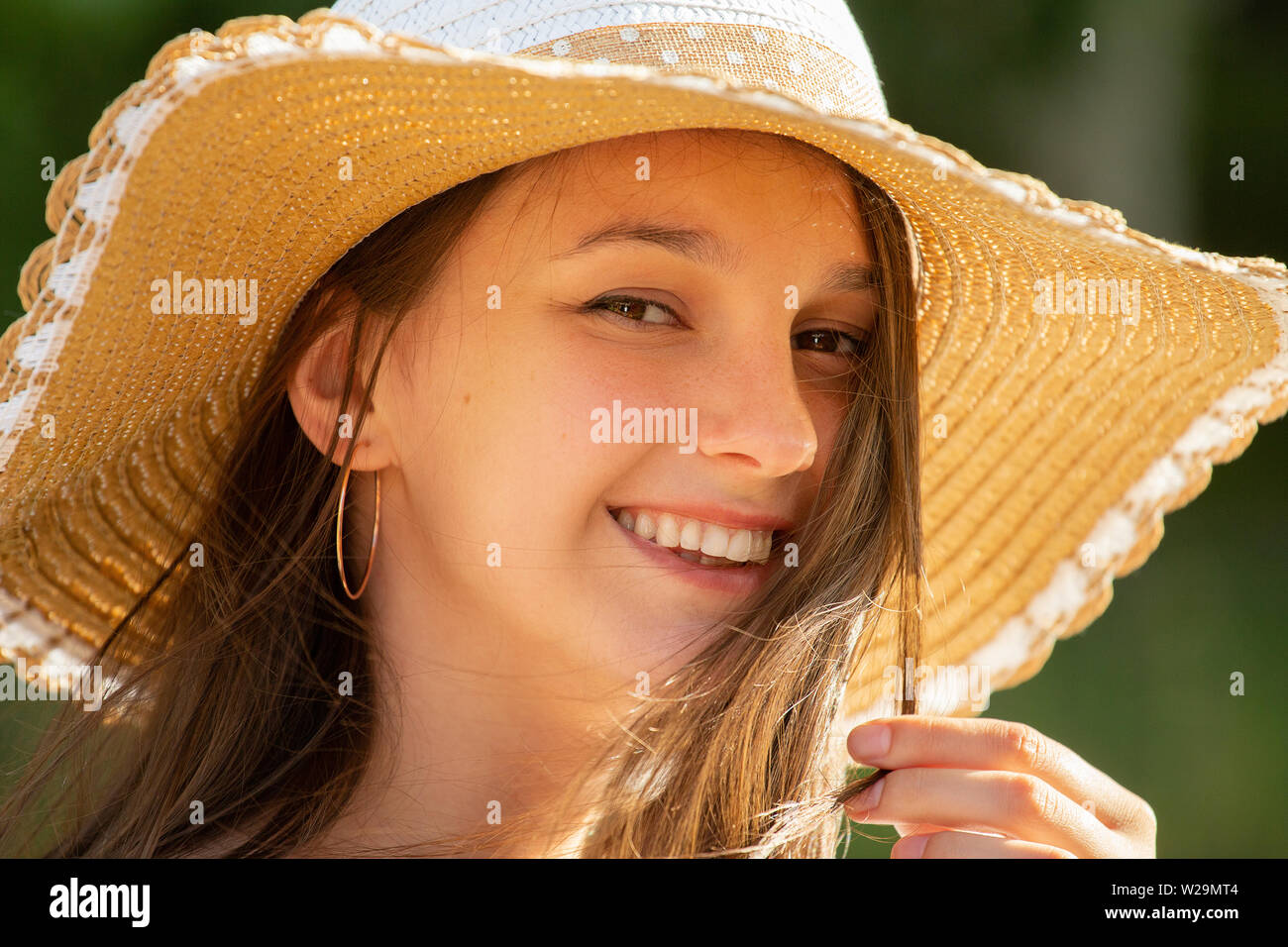 pretty girl in sun hat in sun light looking at camera, laughing toned ...