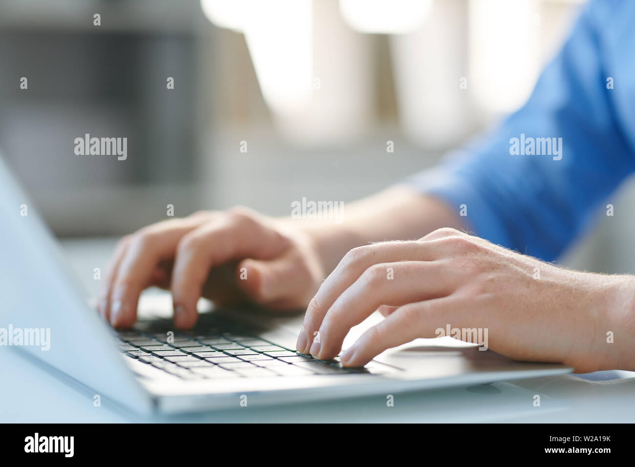 Hands of young mobile male employee pressing keys of laptop keypad ...