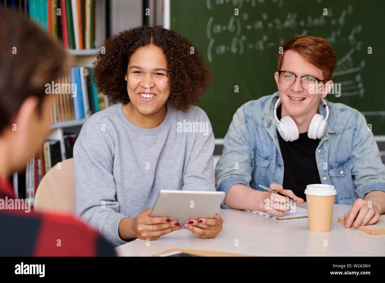 Cheerful girl and her groupmate listening to one of guys during ...