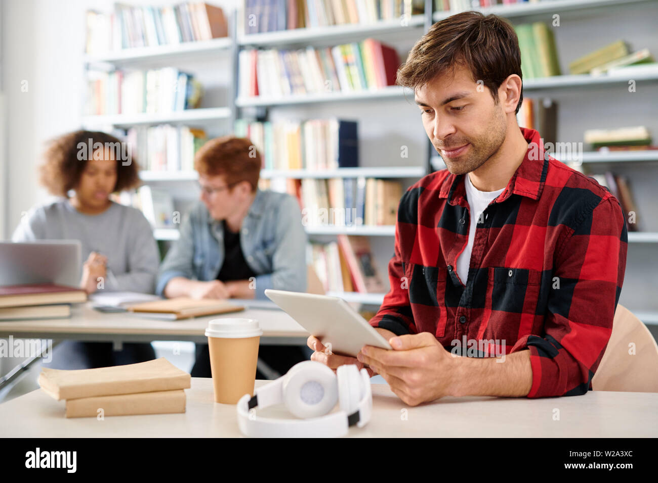 Young mobile student with touchpad watching online video by desk Stock ...