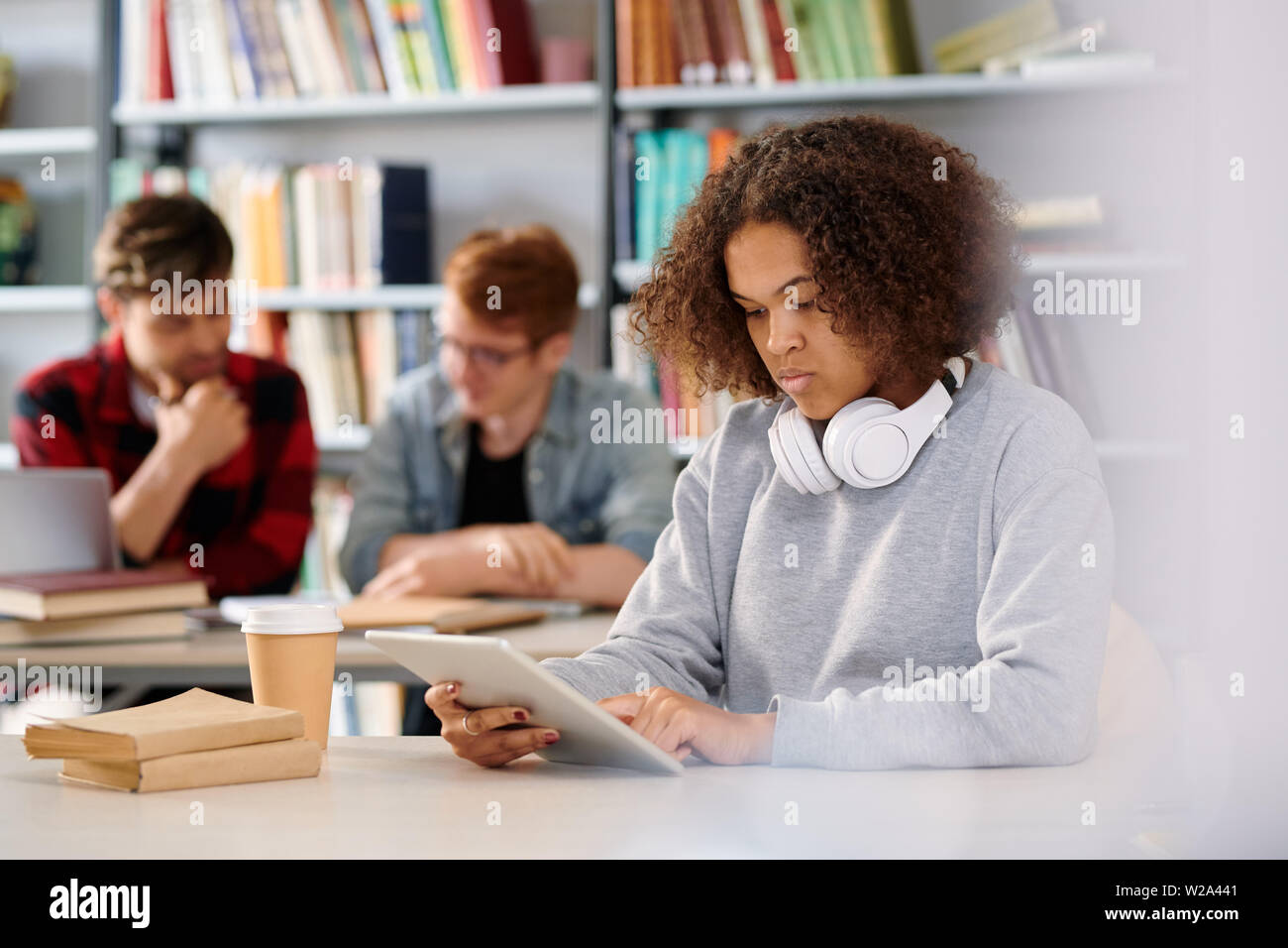Serious girl sitting by desk at break and using touchpad Stock Photo ...