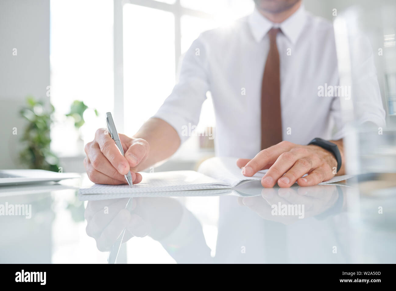 Elegant contemporary businessman making working notes in copybook Stock ...