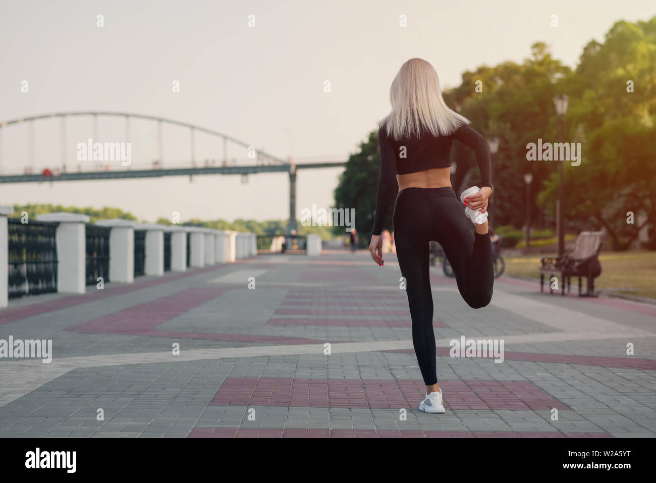 Back view of young fitness woman runner stretching legs before run outdoors Stock Photo - Alamy