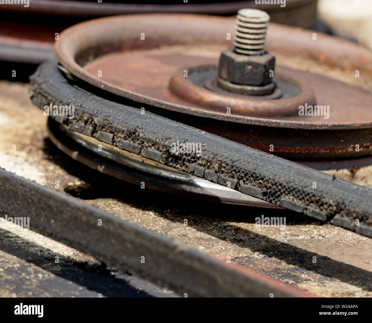 Old, cracked, and worn drive belt and pulley on a lawn mower deck ...