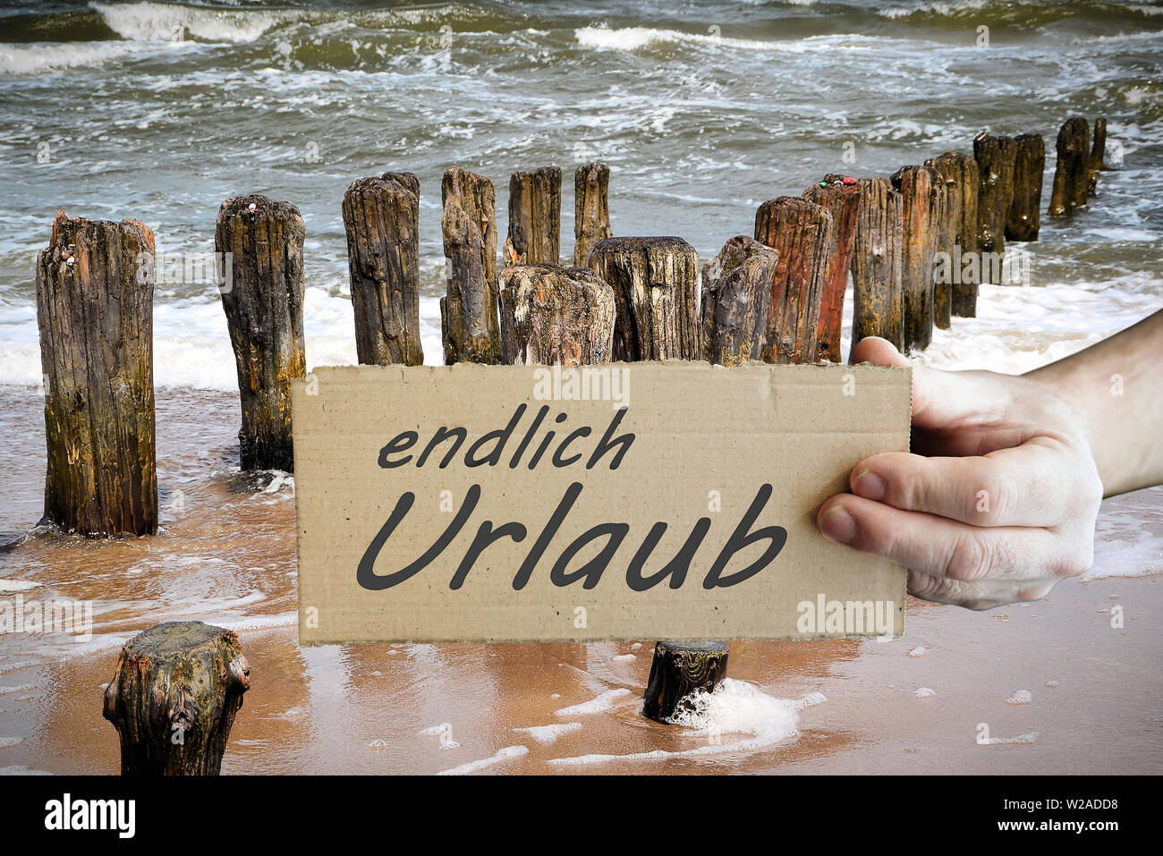 A hand holding a sign that says "finally holiday" on the Baltic Sea ...