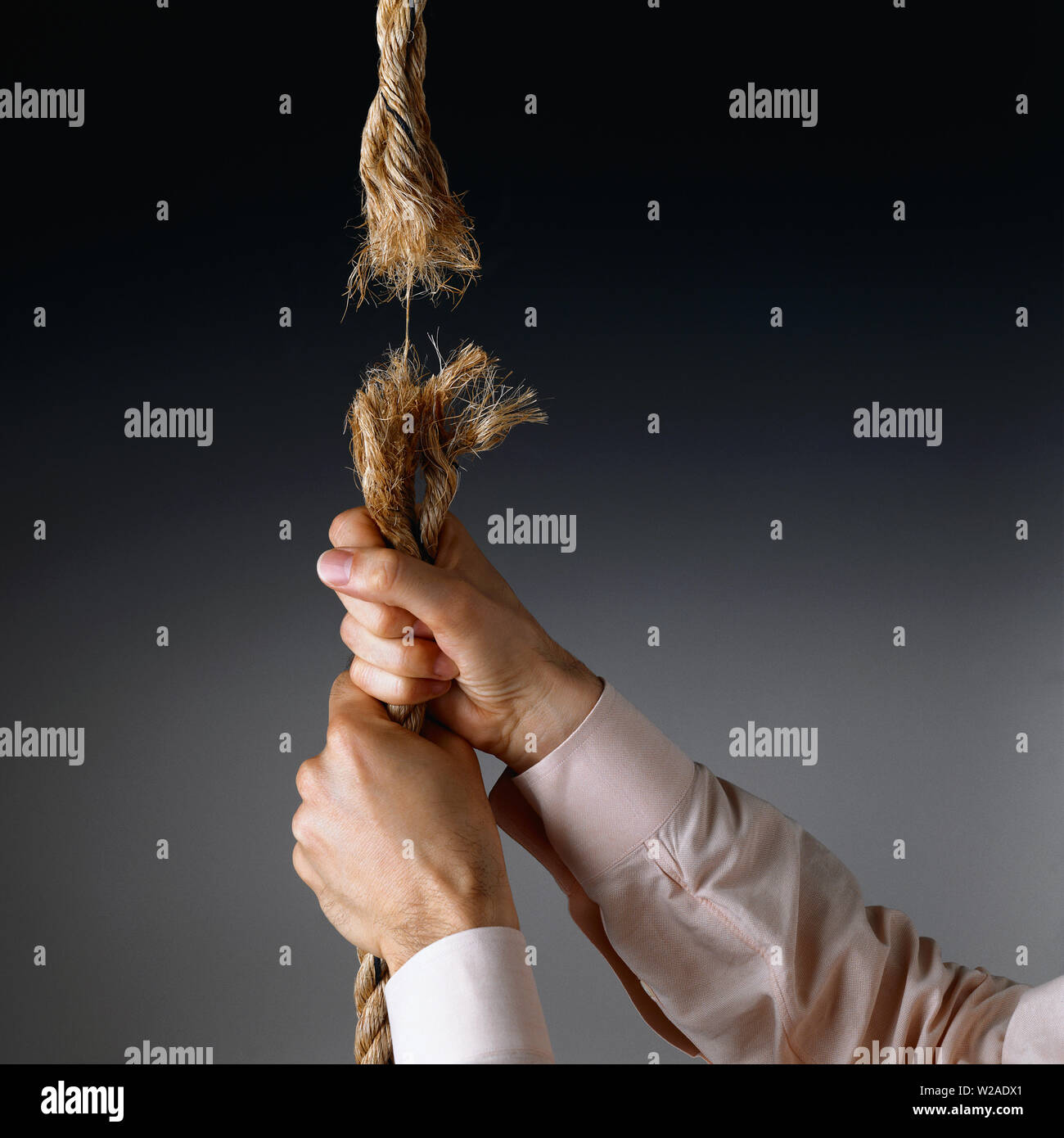 Man Holding Onto The Bottom Of A Rope That Only A String Of Rope Is Keeping The Rope Together