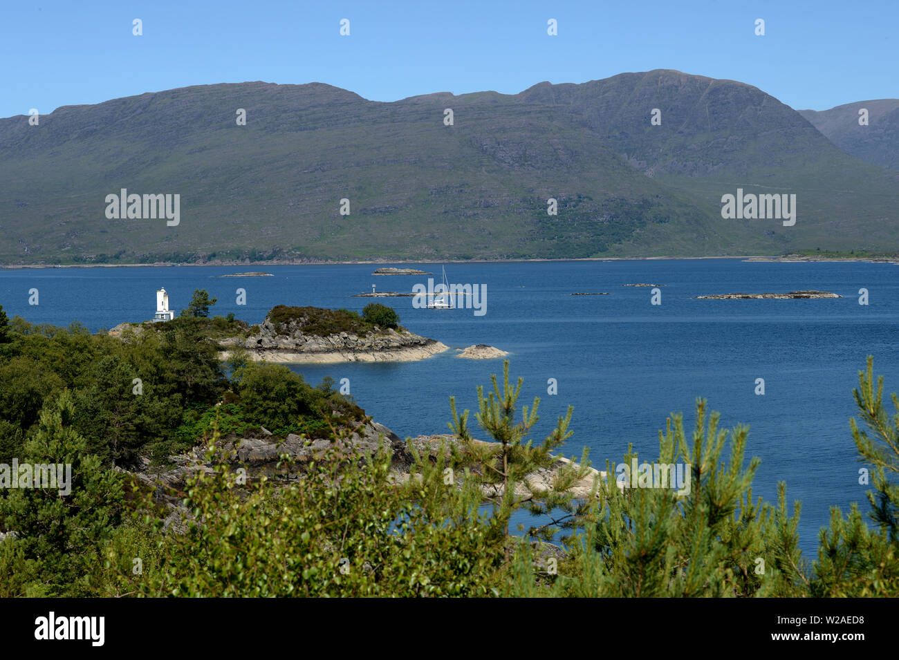 Plockton Lighthouse on the island of Eilean-a-Chait with mountain ...