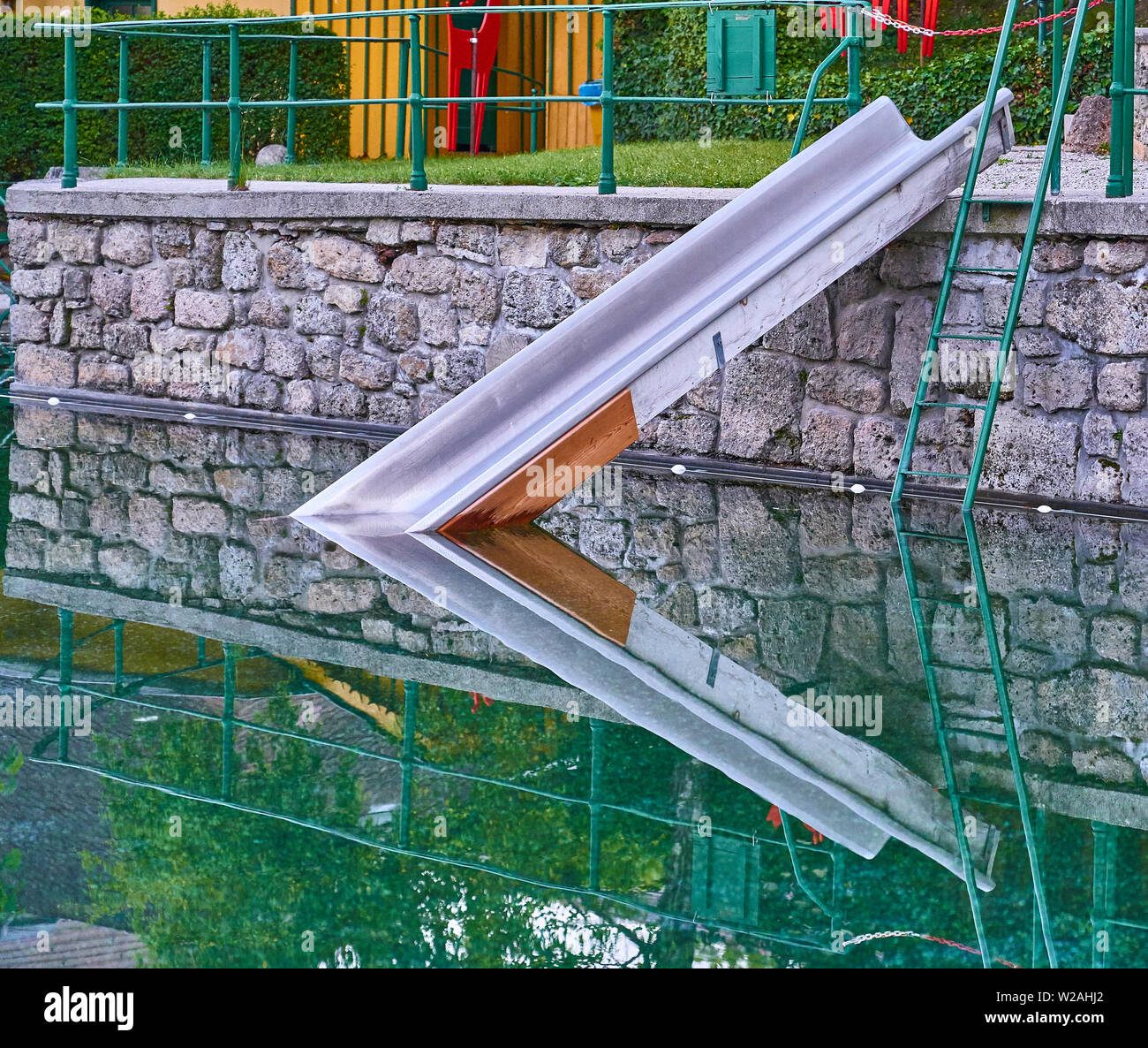 A historic natural thermal pool in Bad Fischau, Austria. A metal slide ...