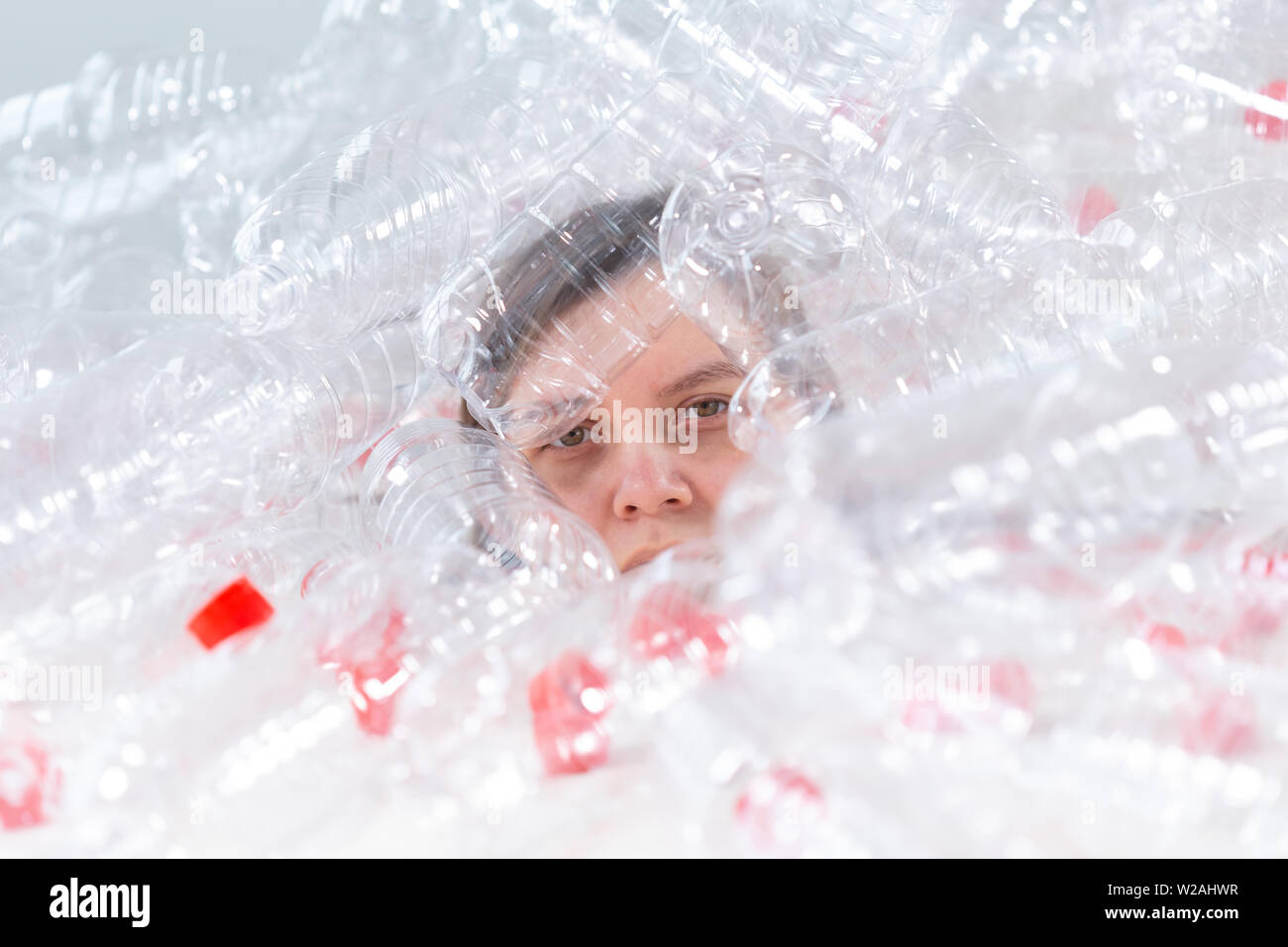 Dehydrated sick woman is lying in a pile of plastic bottles ...