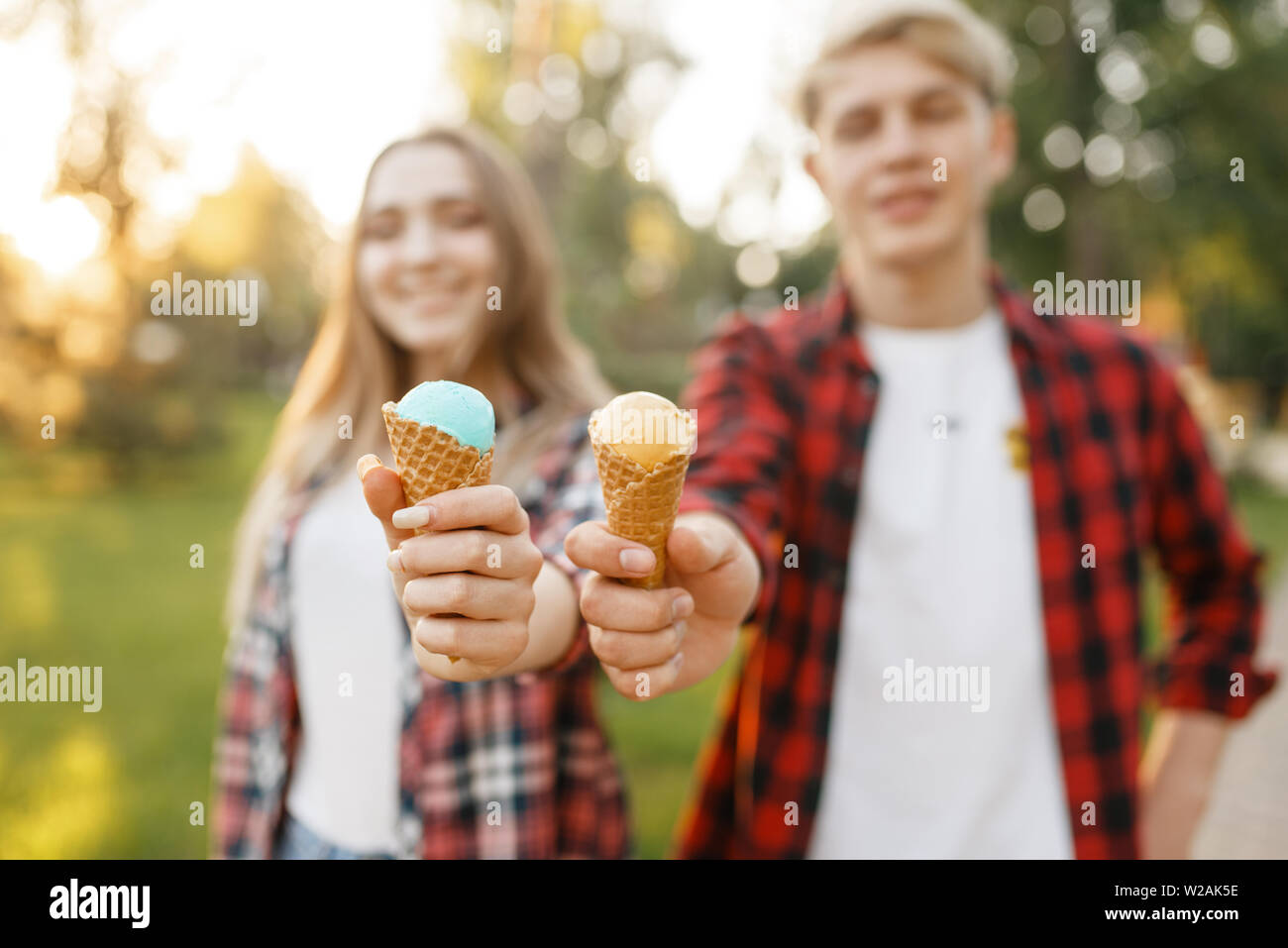 Young couple with ice cream walking in summer park. Boyfriend and ...