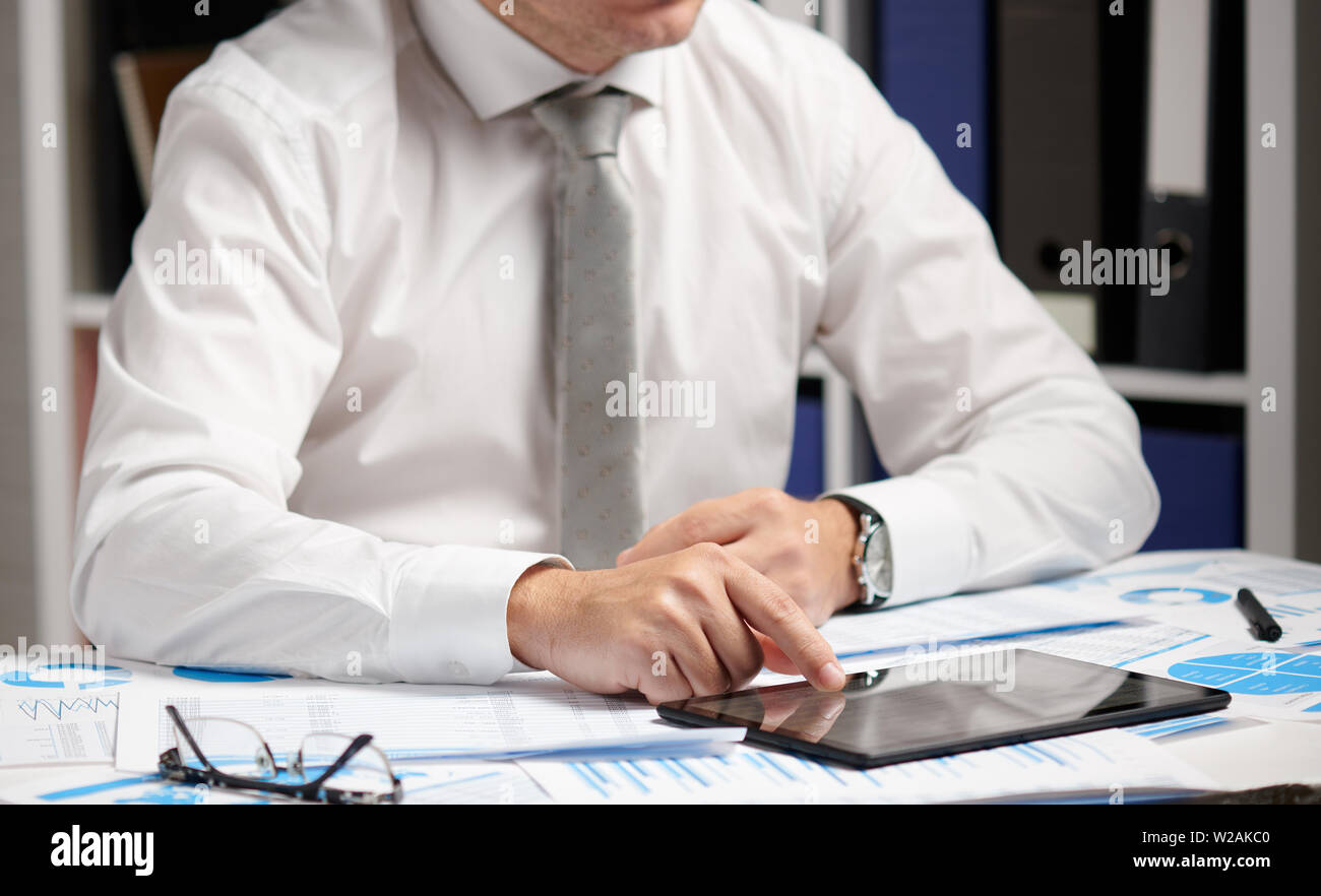 Businessman working with tablet pc, calculating, reading and writing ...