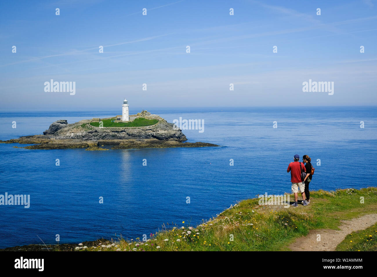A couple stand on the South West Coast Path at Godrevy with a view ...