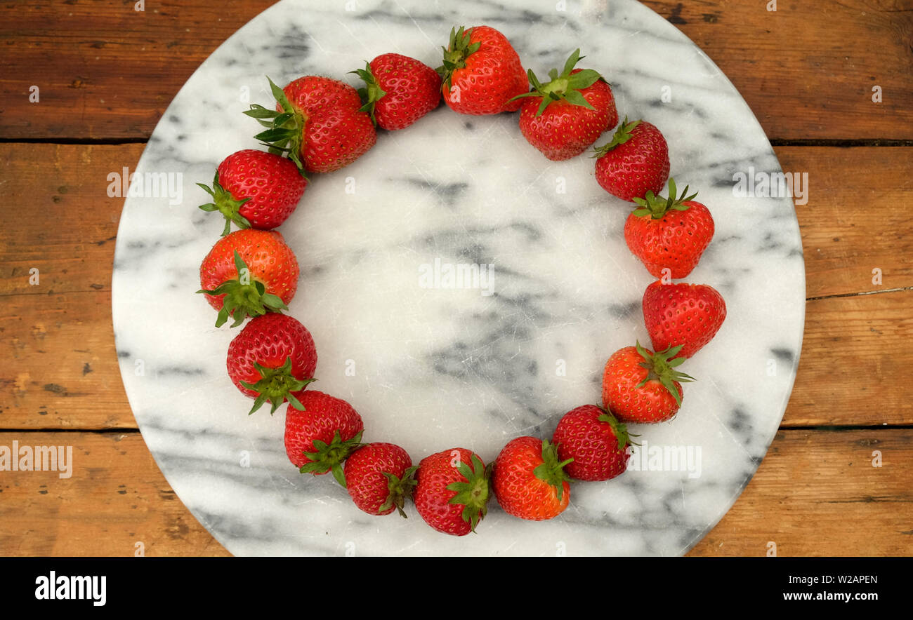 sixteen red ripe strawberries positioned in a circular shape on a ...