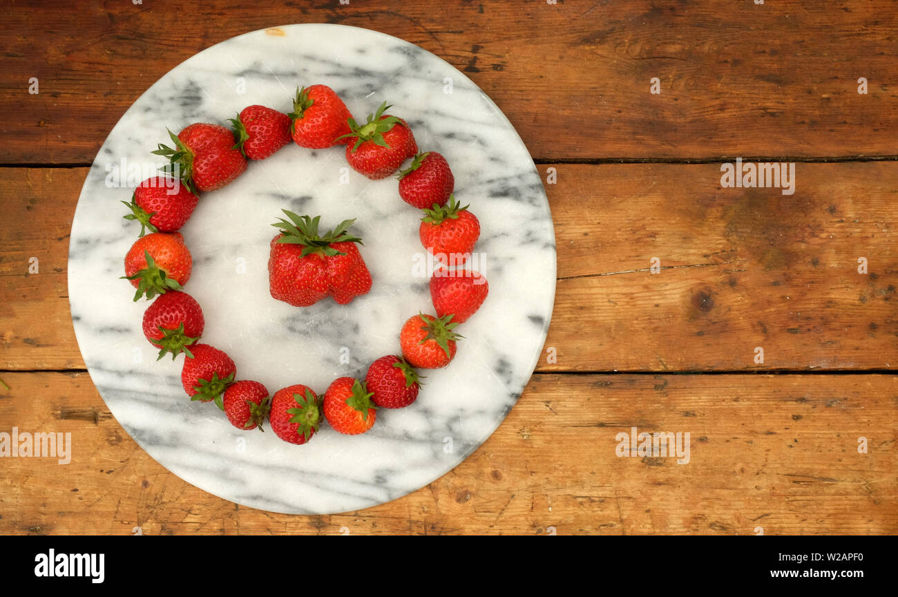 sixteen red ripe strawberries positioned in a circular shape on a ...
