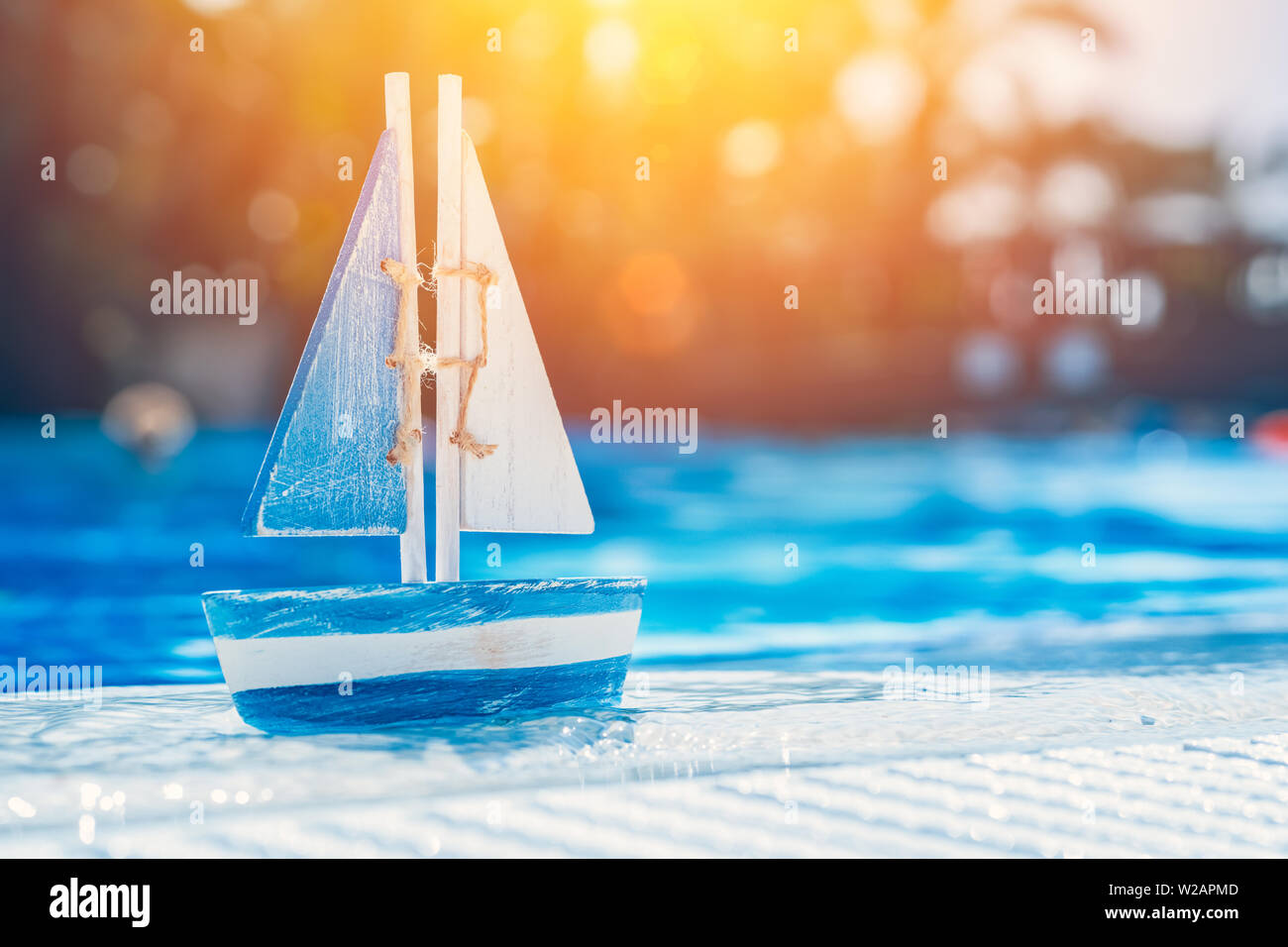 wooden toy sailboat by the swimming pool in summertime. Vacation and ...