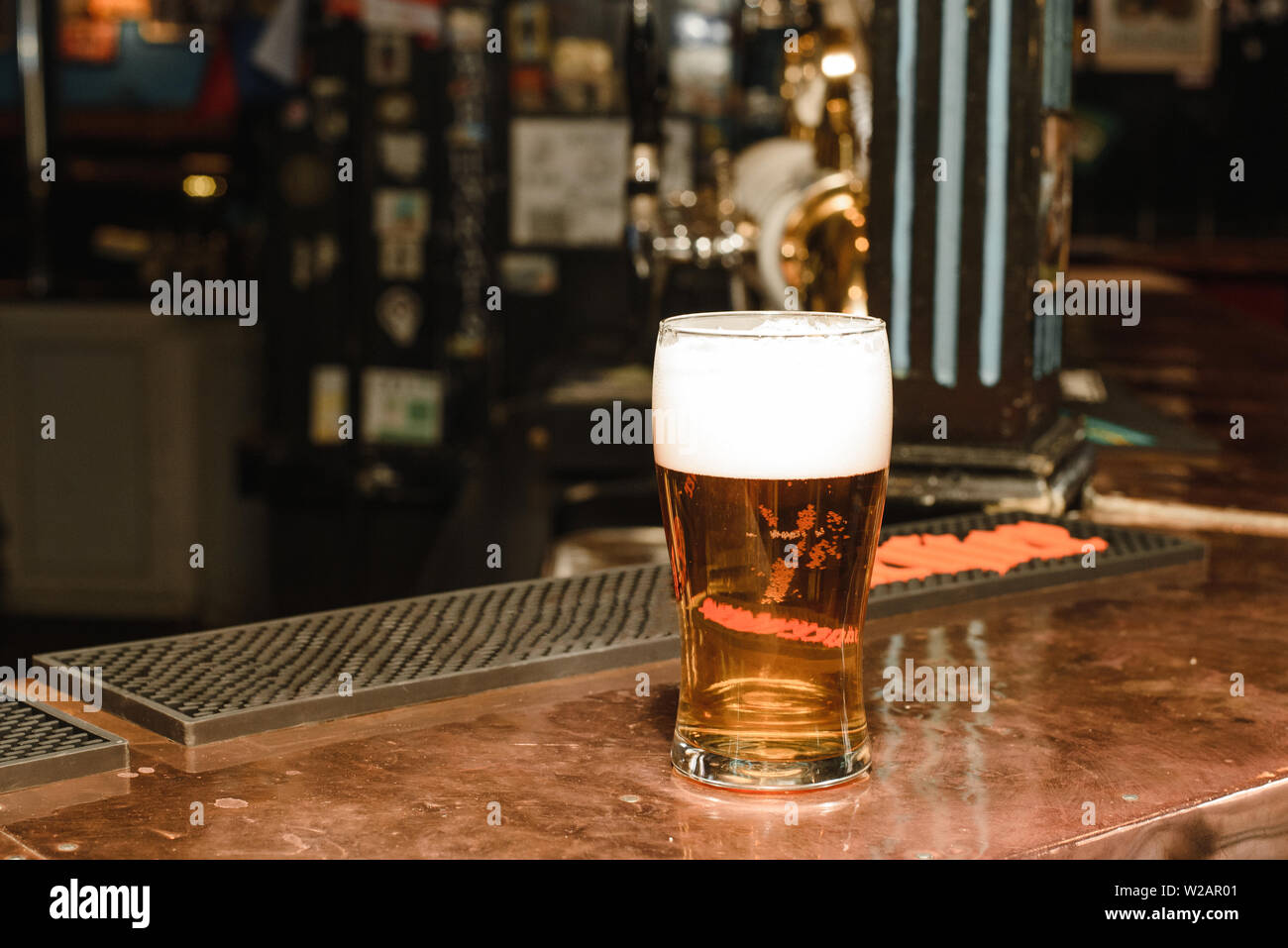 a glass of beer in a popular bar. Pint of foamy drink in a restaurant ...