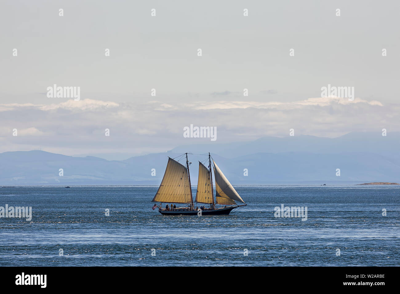 A vintage style two masted sailing ship out on the open waters in the ...