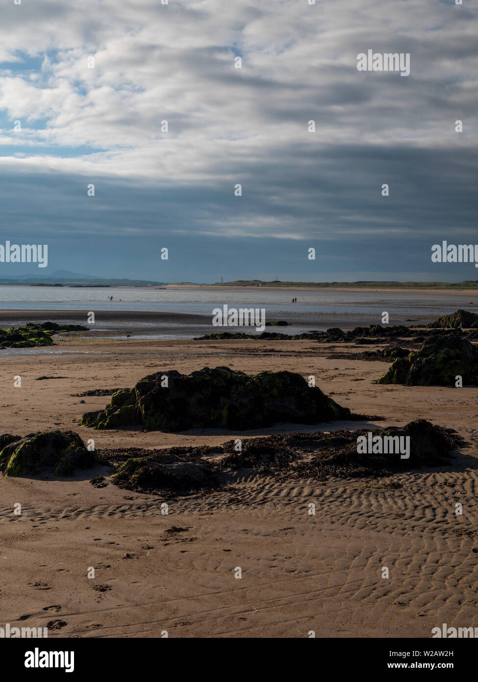 Rocks and sand with wispy clouds on Traeth Crigyll beach, Anglesey ...
