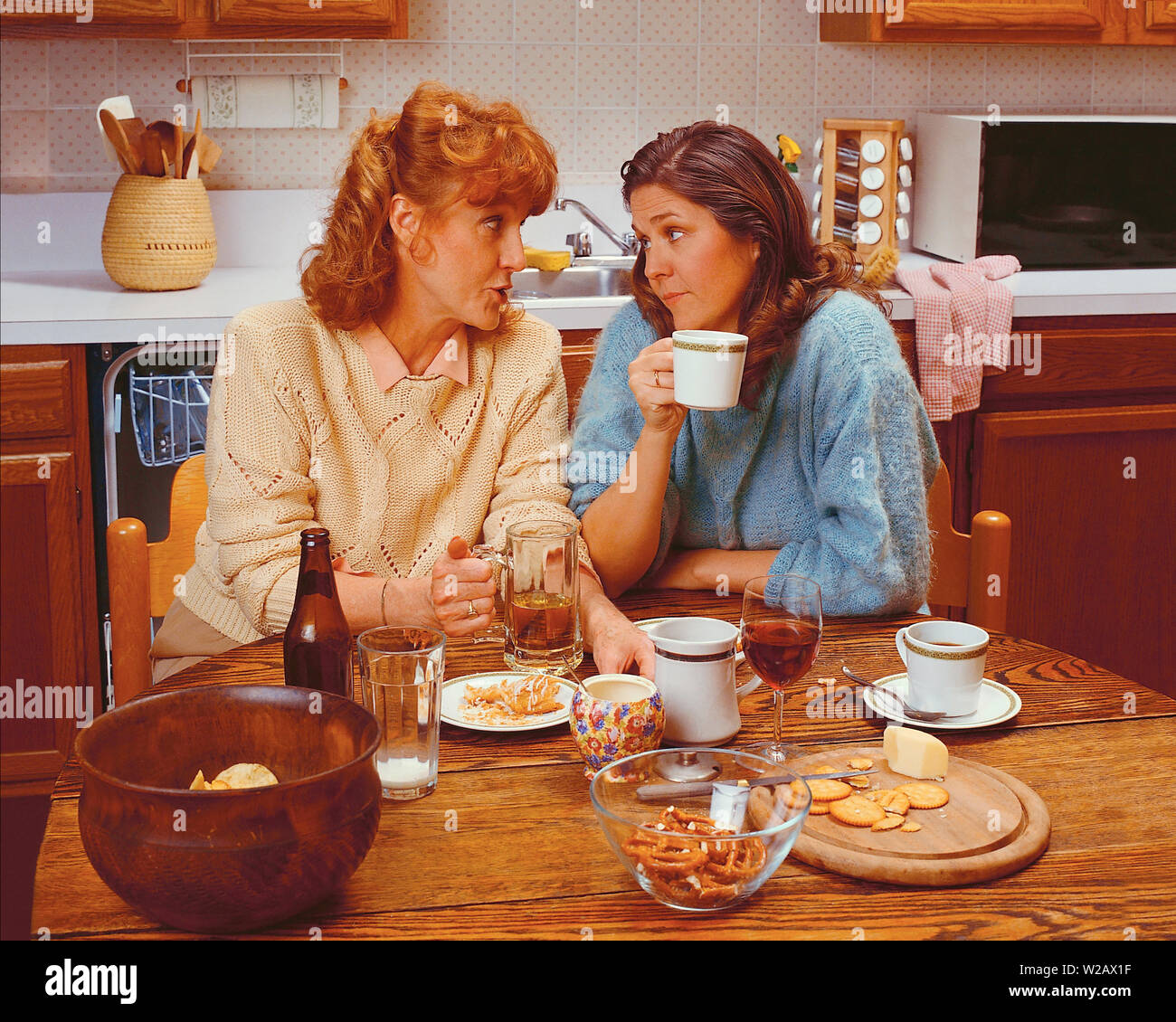 Two women talking in the kitchen over coffee Stock Photo - Alamy