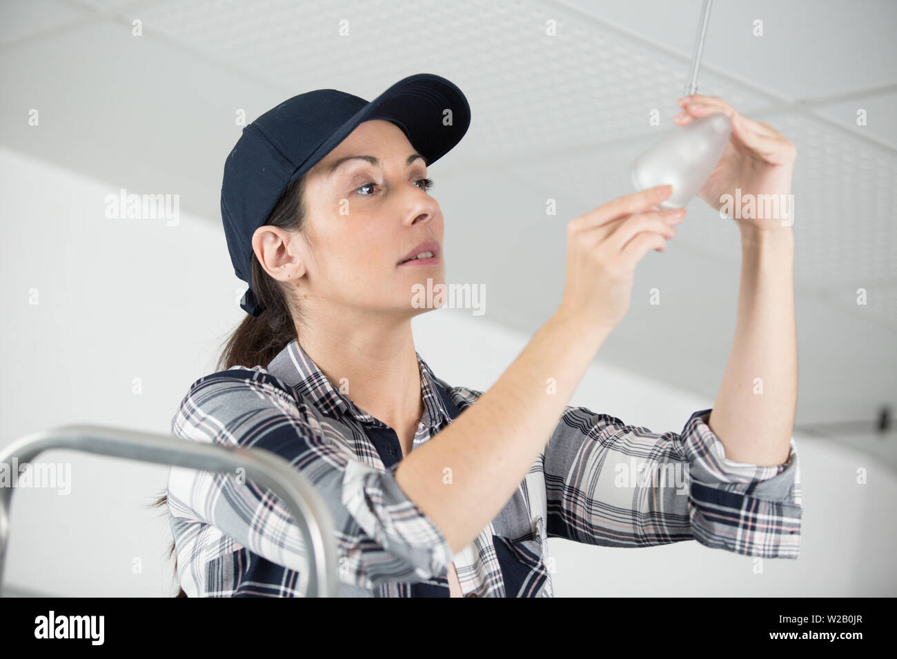 Woman changing lightbulb hi-res stock photography and images - Alamy