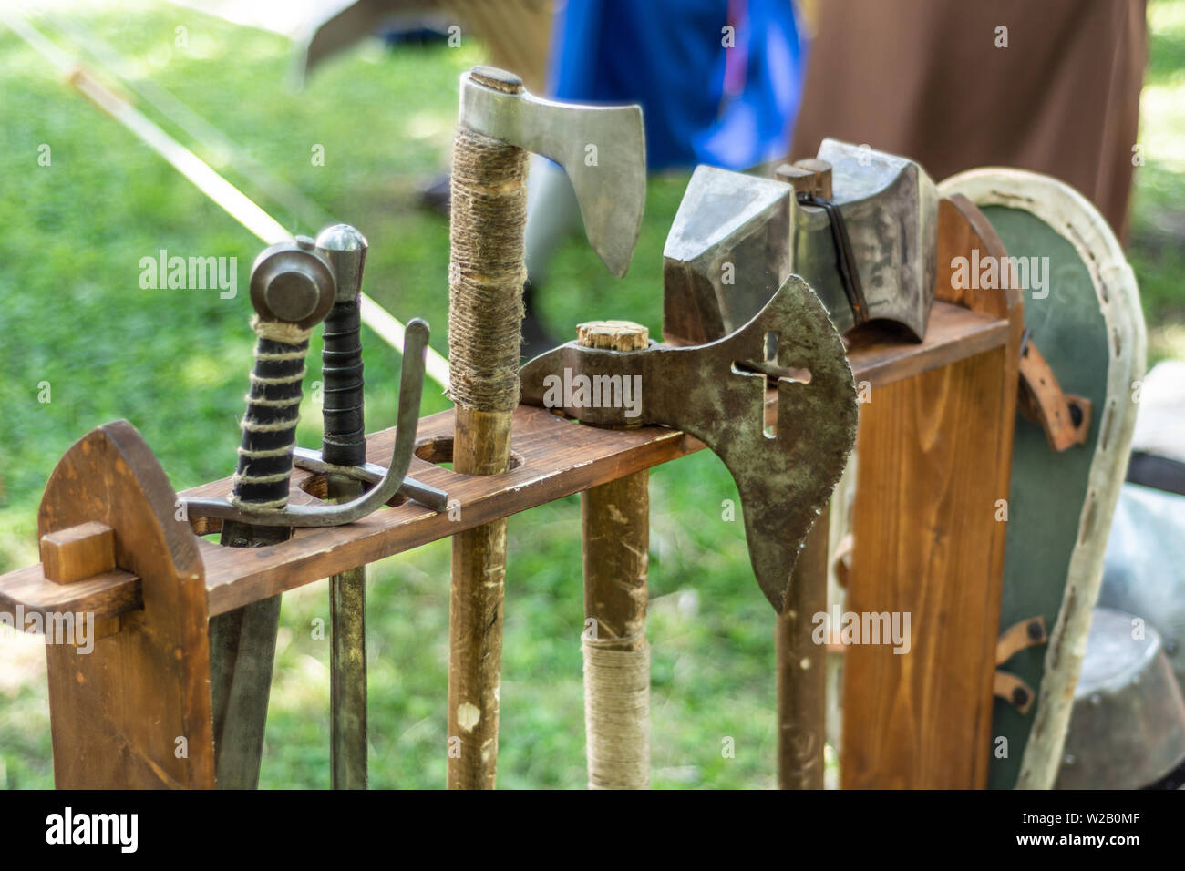 Medieval metal ax and sword in a wooden stand on the festival. Old dark ...