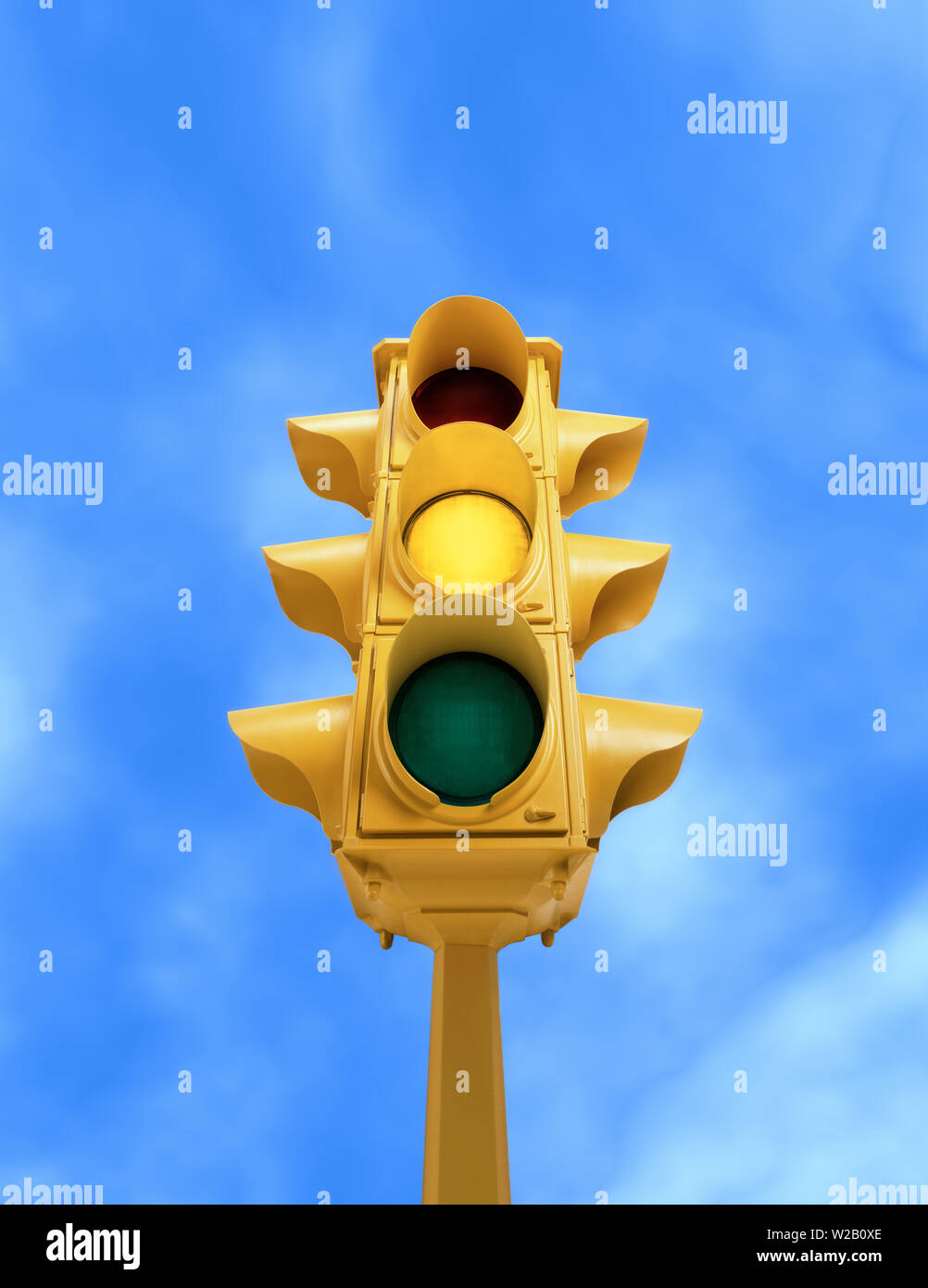 Upward view of tall vintage yellow traffic signal with yellow light on ...