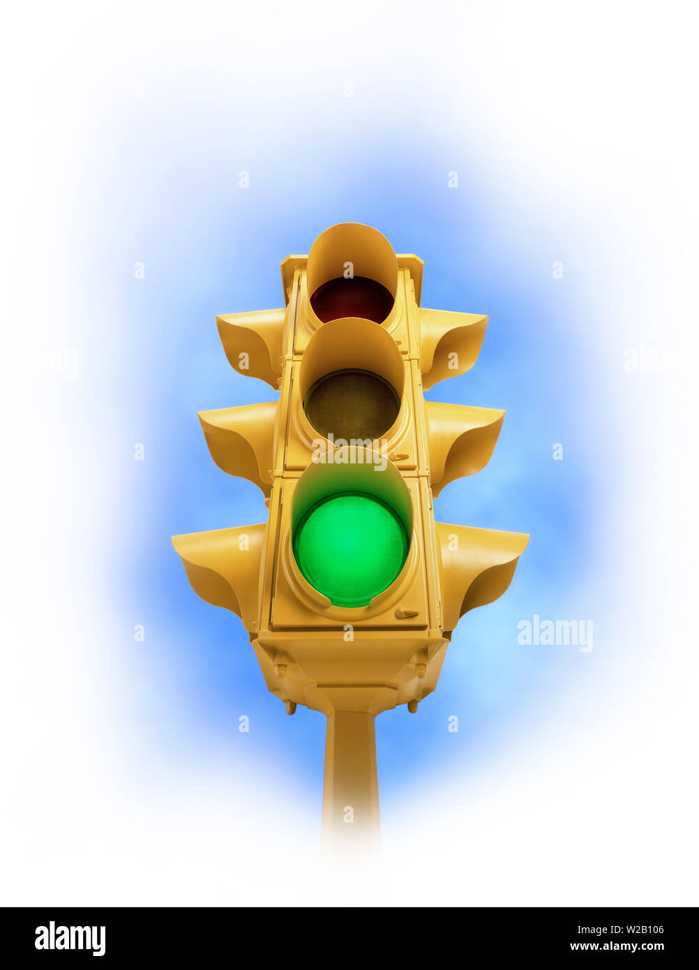 Upward view of tall vintage yellow traffic signal with green light on ...
