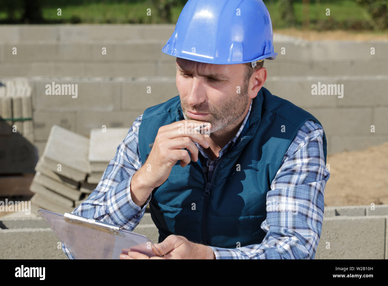 male builder smoking cigarette while checking a clipboard Stock Photo ...