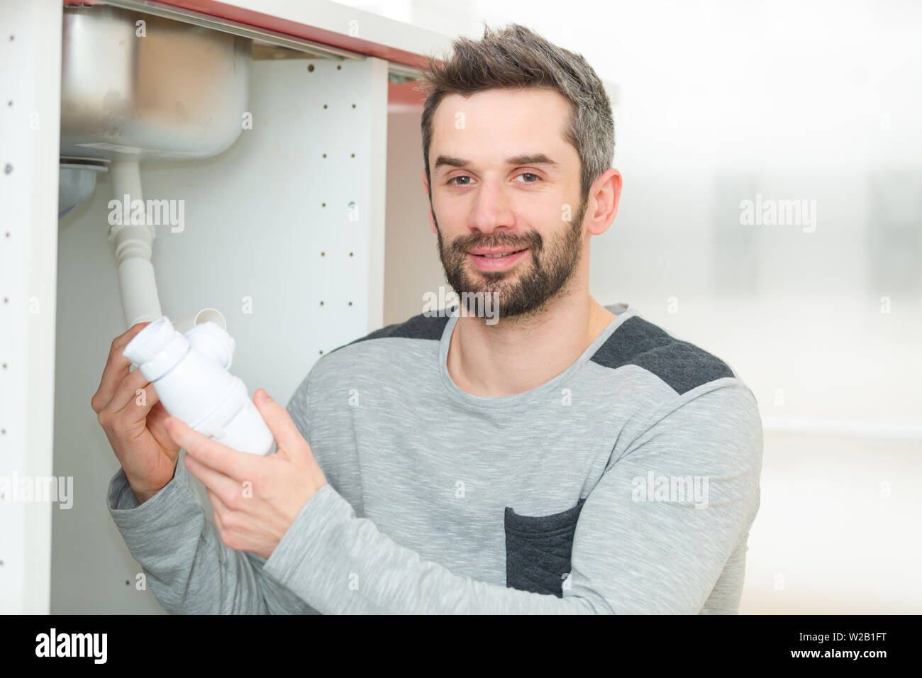 portrait of man fitting syphon to waste water pipe Stock Photo - Alamy