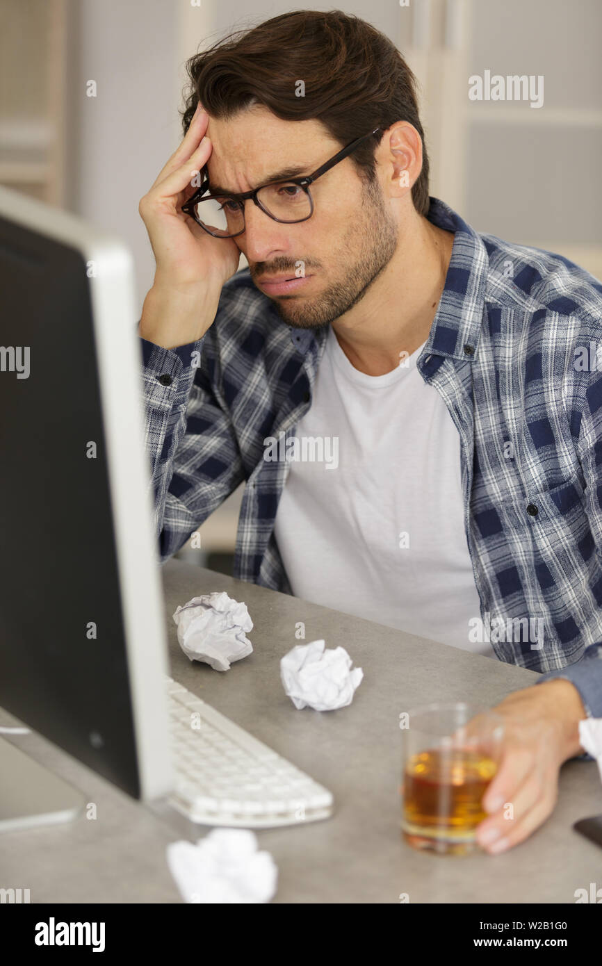 man using computer and drinking alcohol crumpled paper around him Stock ...