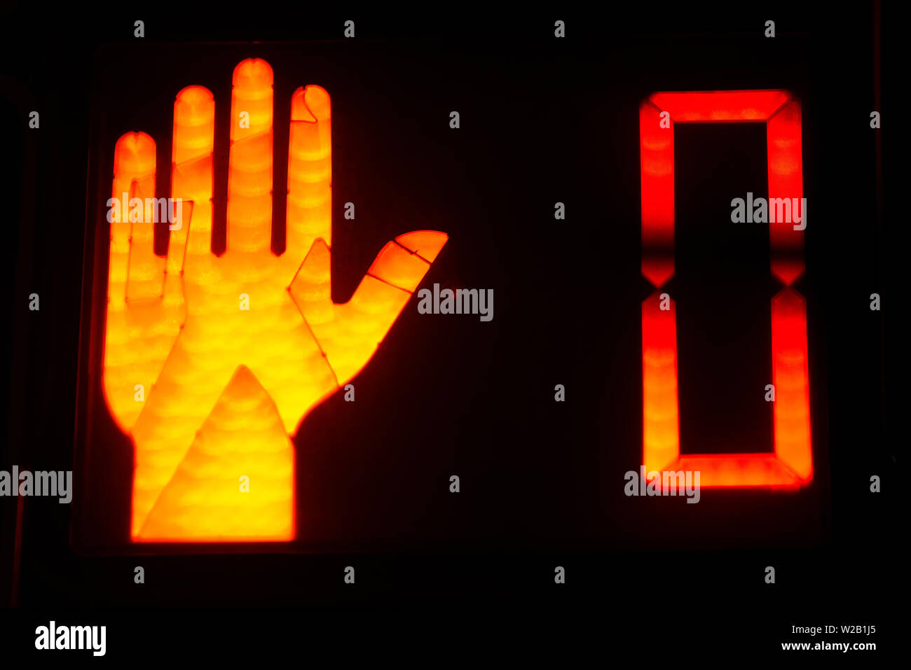 Illuminated orange / red stop walking sign with zero '0' on the timer ...