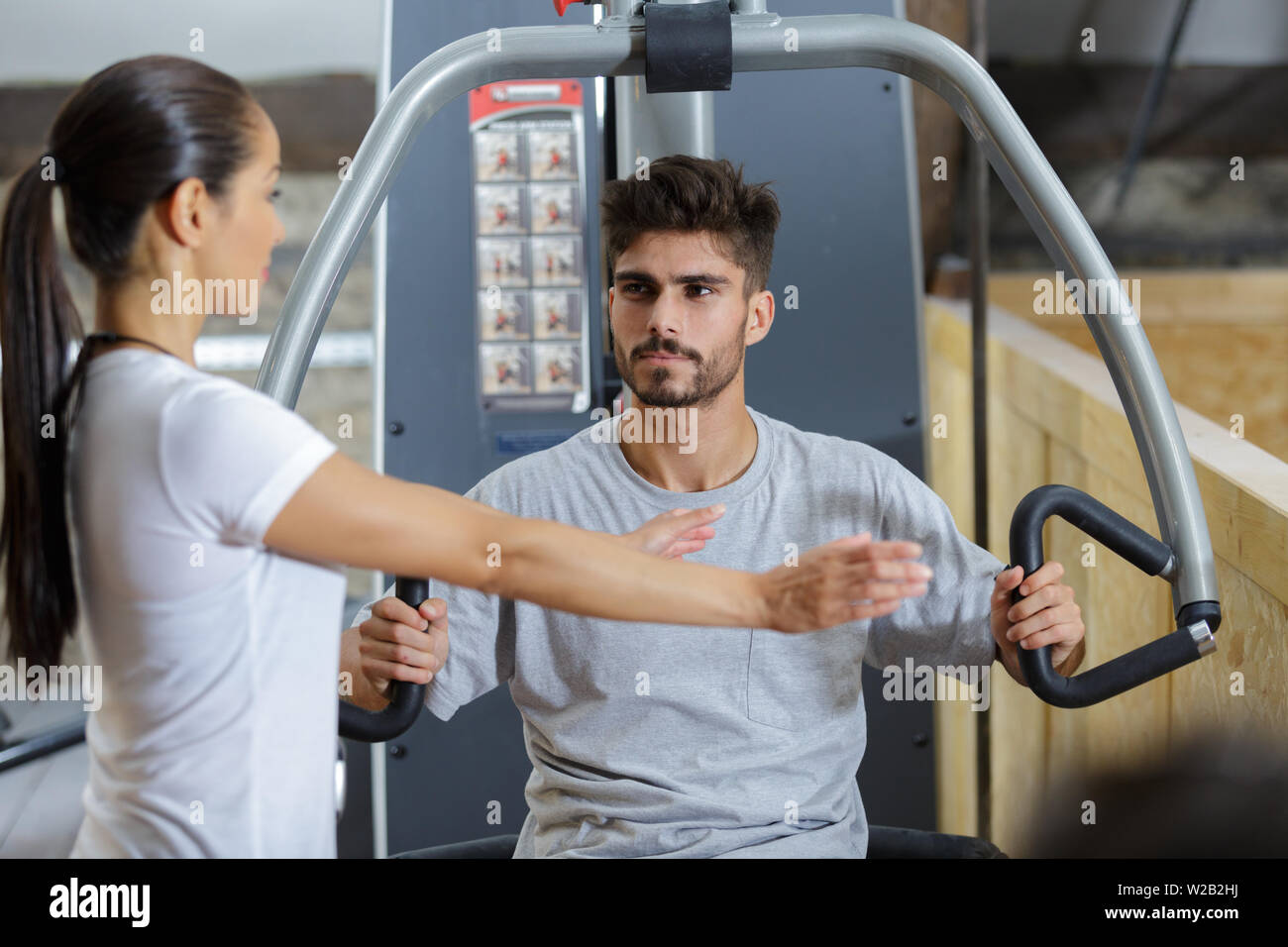 gym trainer showing how to use a machine to client Stock Photo - Alamy