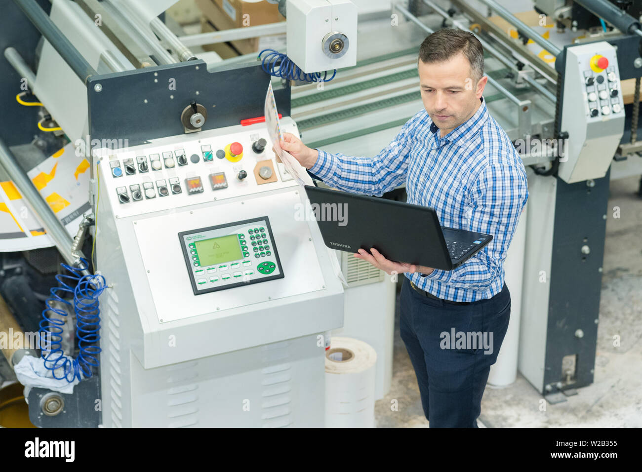 technician using laptop next to production line Stock Photo - Alamy